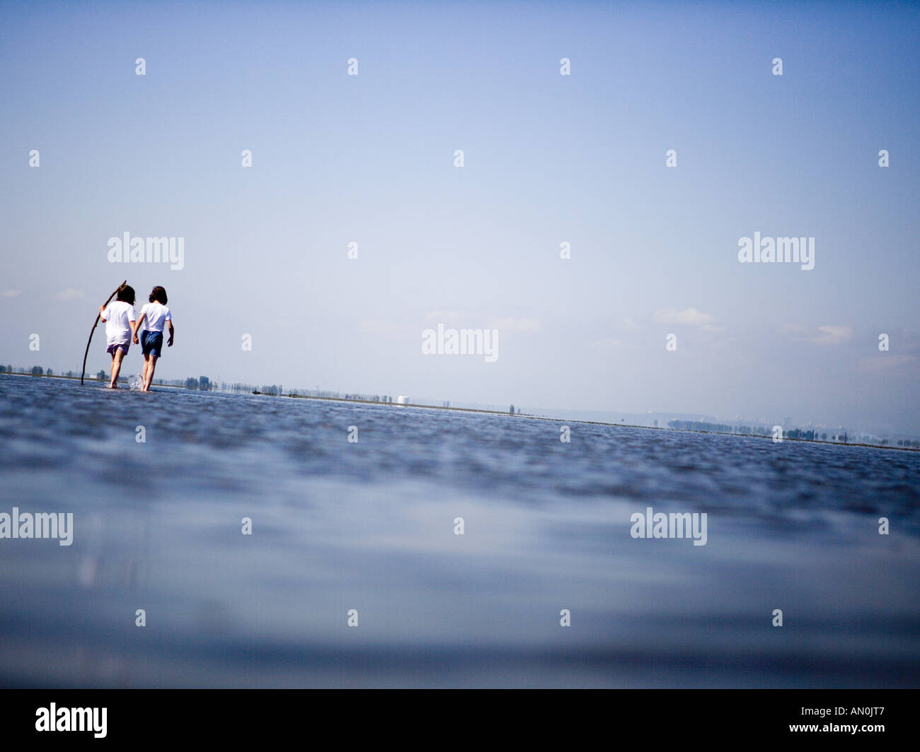 Rear view of two people wading in water Stock Photo - Alamy