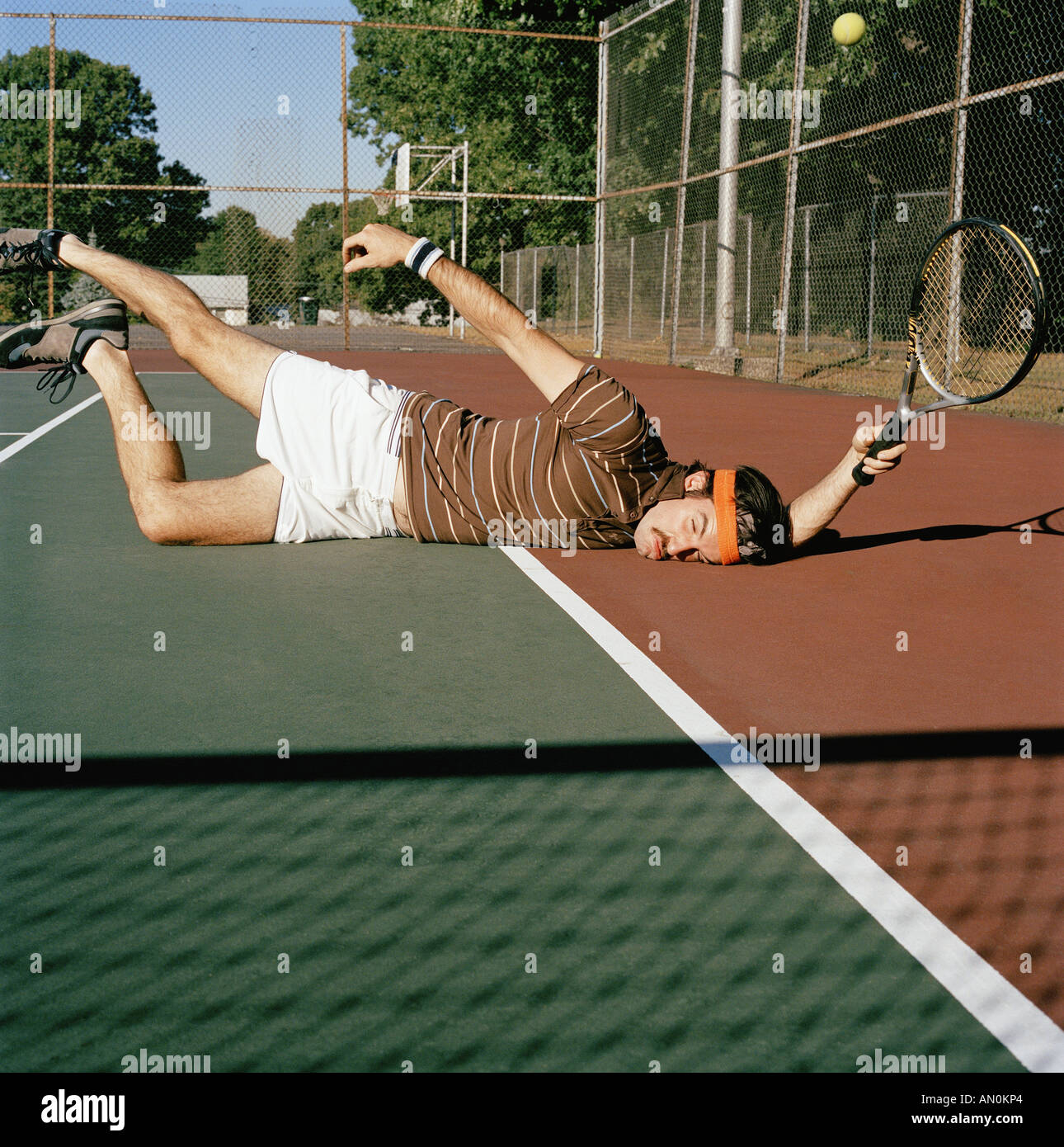 Young man falling down on a tennis court Stock Photo - Alamy
