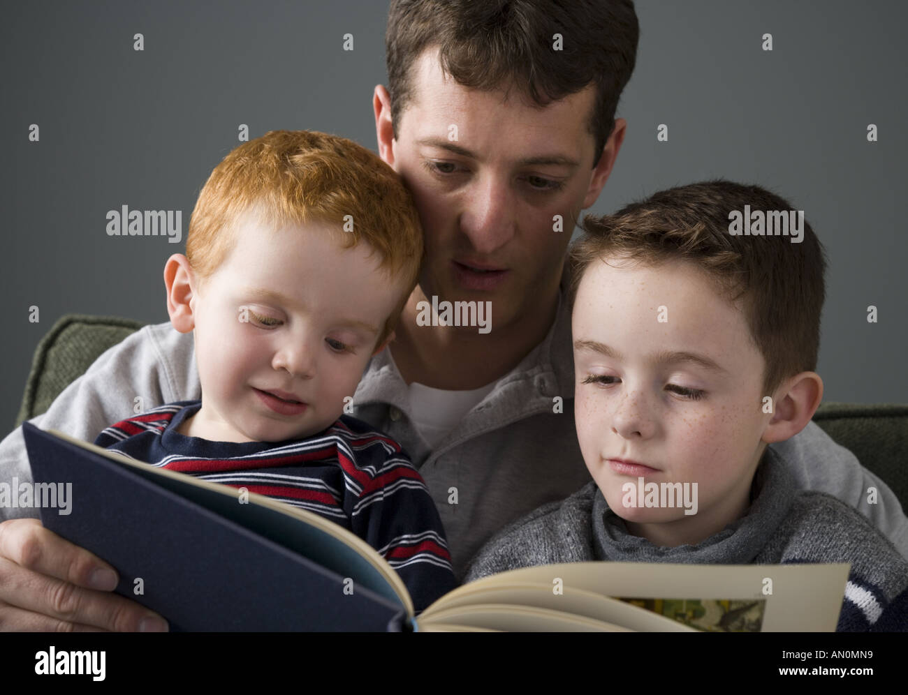 Close up of a father reading a book with his two sons Stock Photo - Alamy