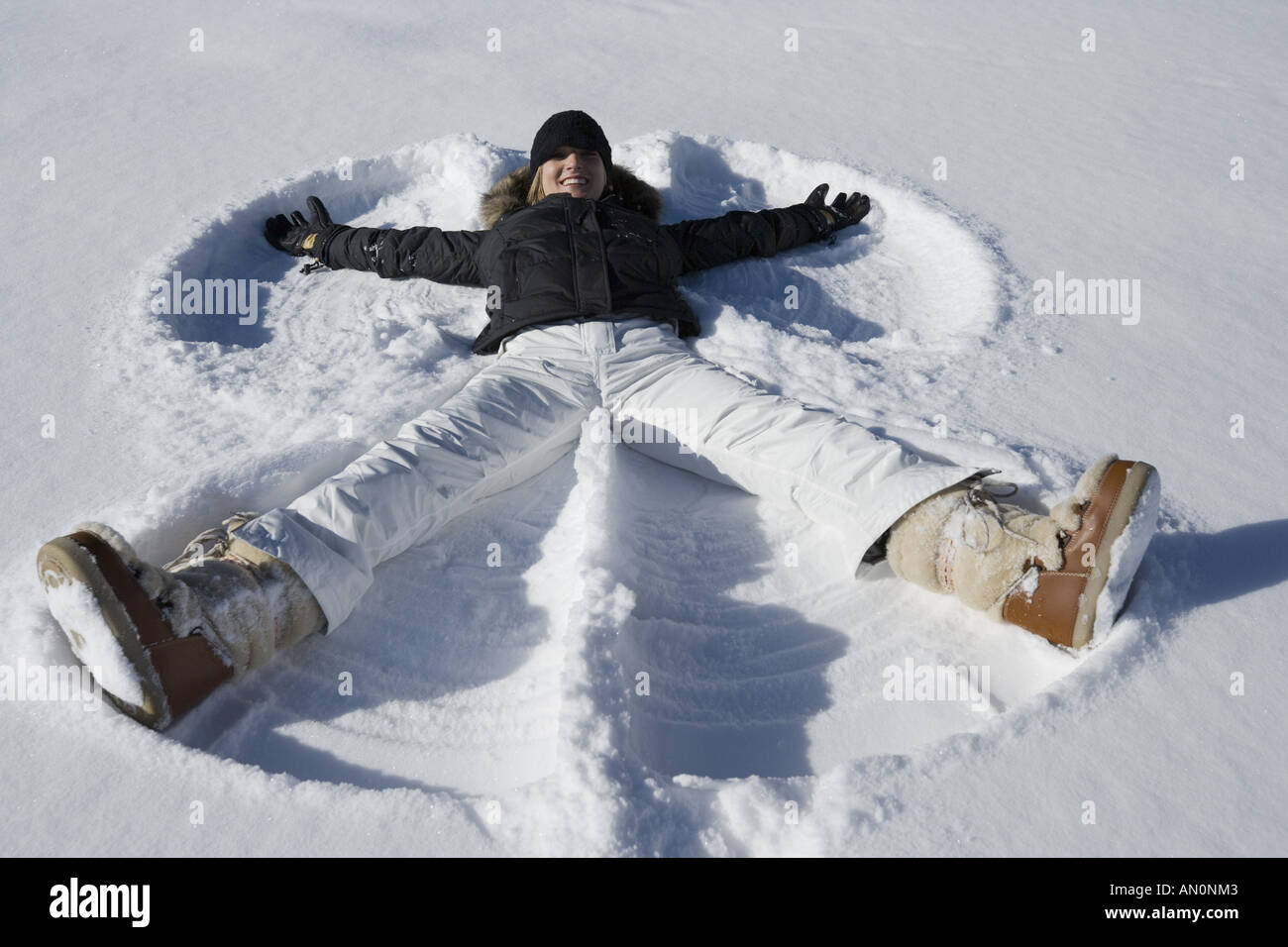 High angle view of a young woman lying in snow making a snow angel ...