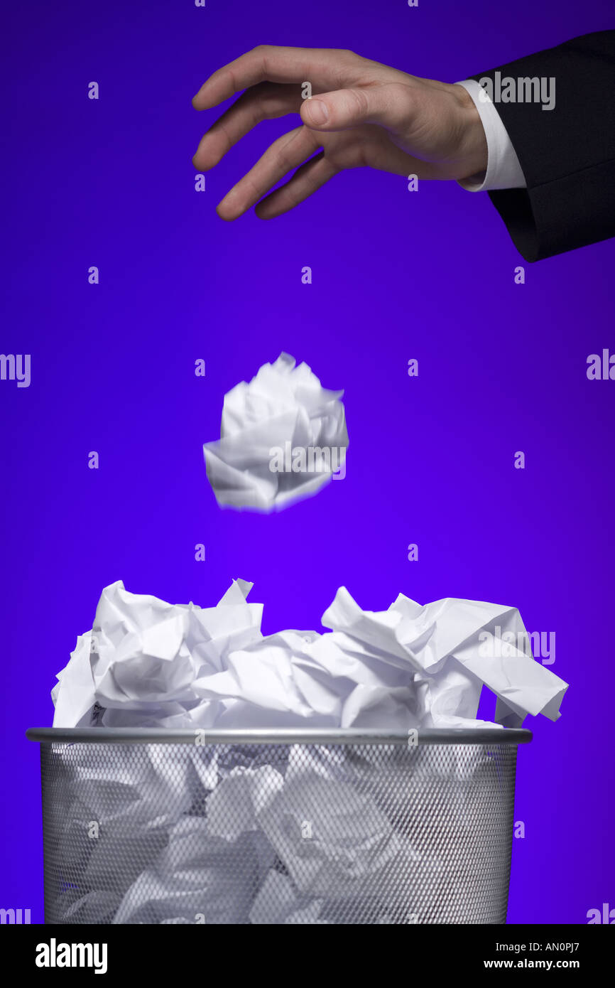 Close up of a businessman s hand throwing a paper ball into a garbage ...