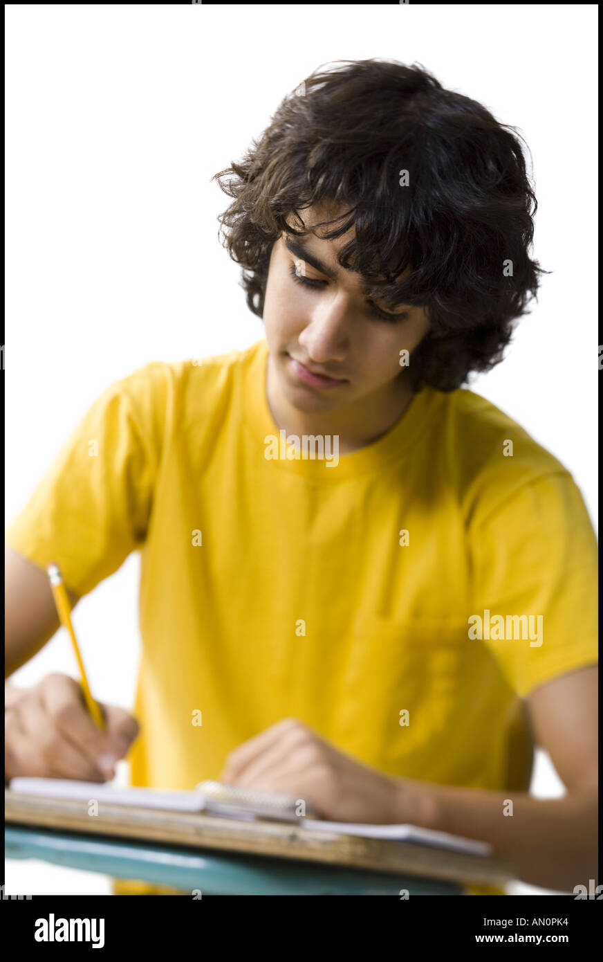Close up of a teenage boy writing at a school desk Stock Photo - Alamy