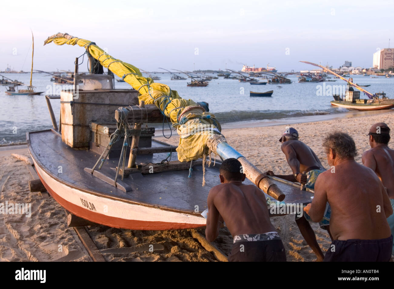 fishermen push a small sail boat known as a jangada to the water for a ...