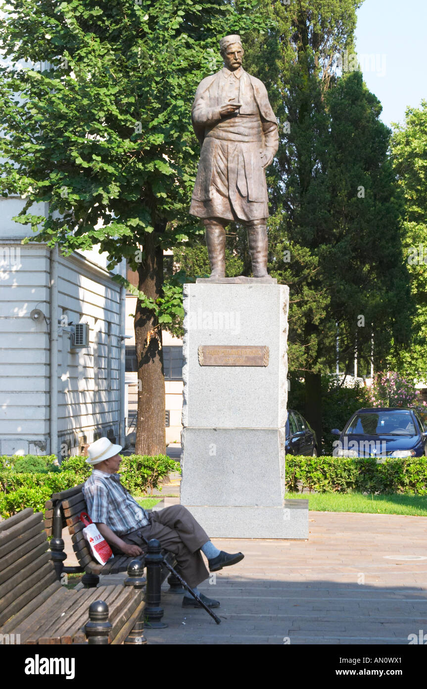 A statue of UNK and an old man with a walking stick sitting on a bench ...
