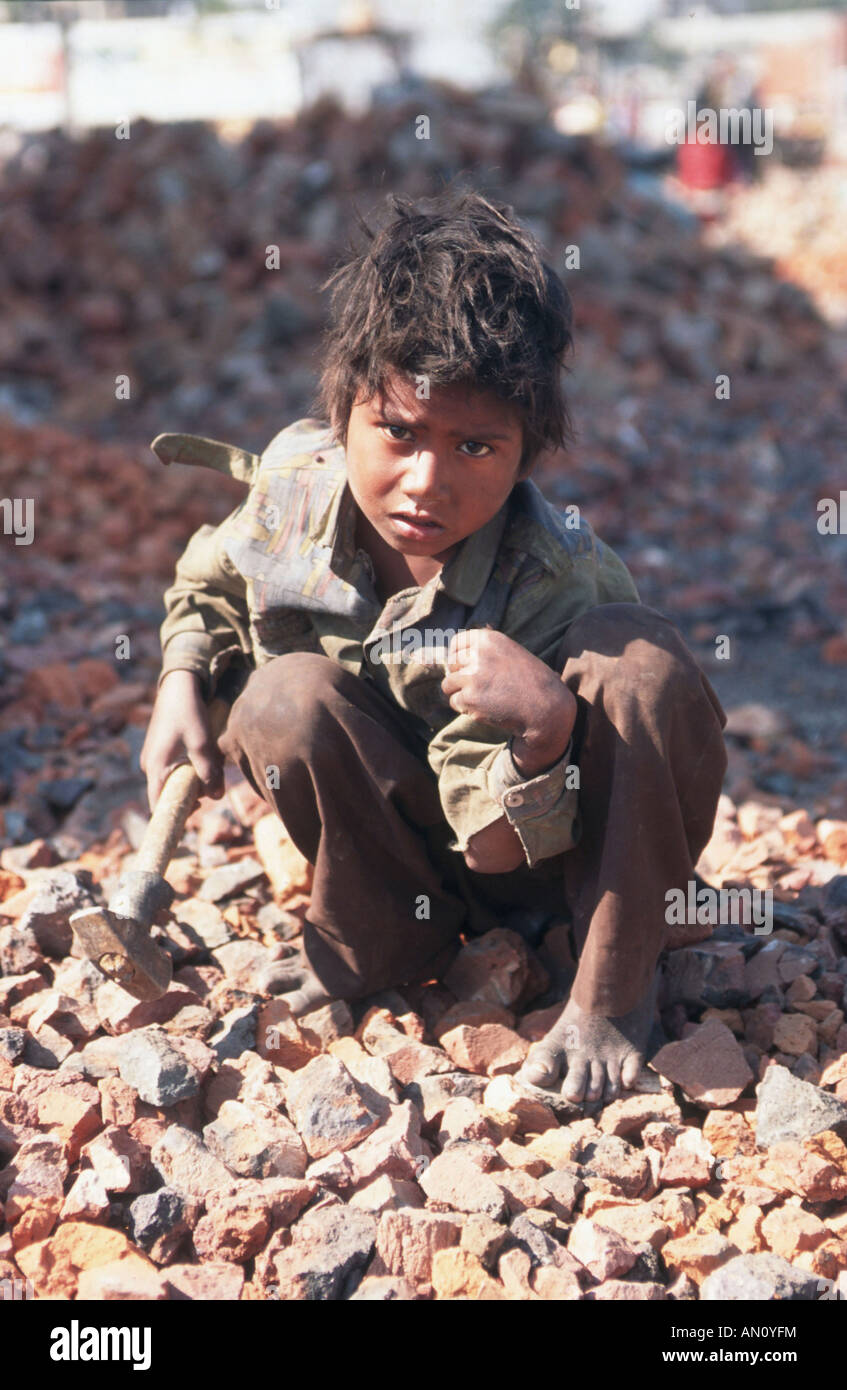 Young boy using hammer to break bricks to be used to mend roads Stock ...