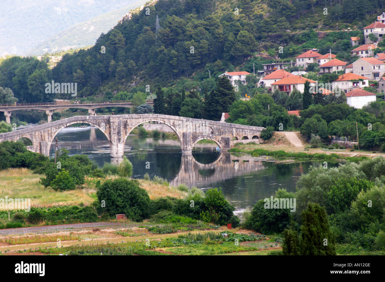 An old Roman stone bridge across the river Trebisnjica. Houses ...