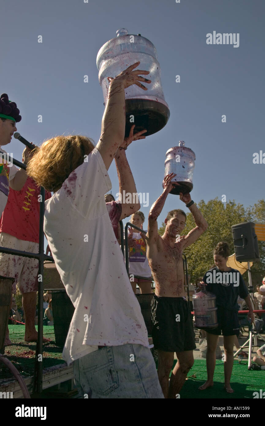 Holding jugs of grape juice output at grape stomping competition at ...