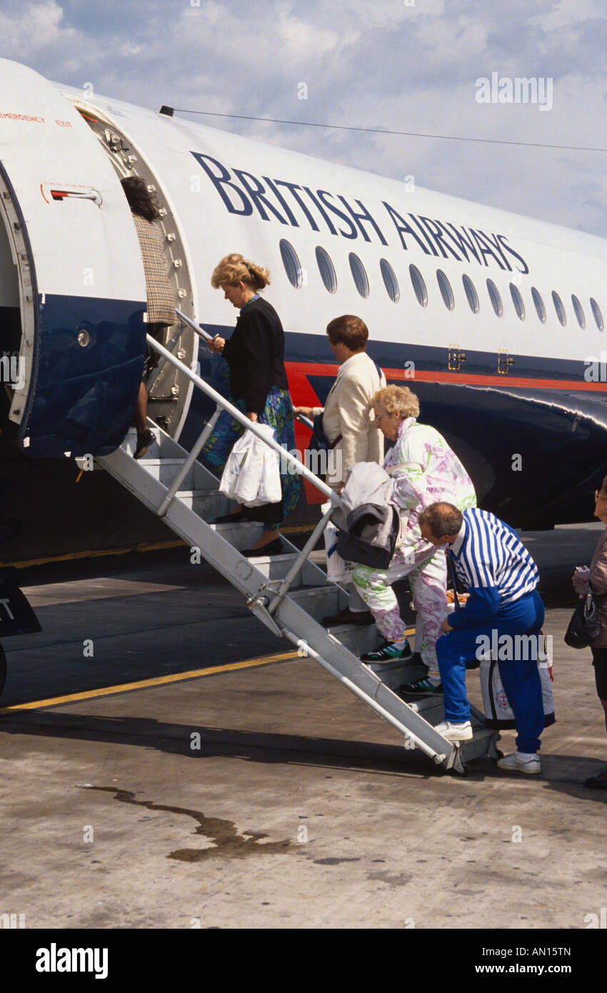 Passengers walking up steps to board aeroplane on airport runway Stock ...
