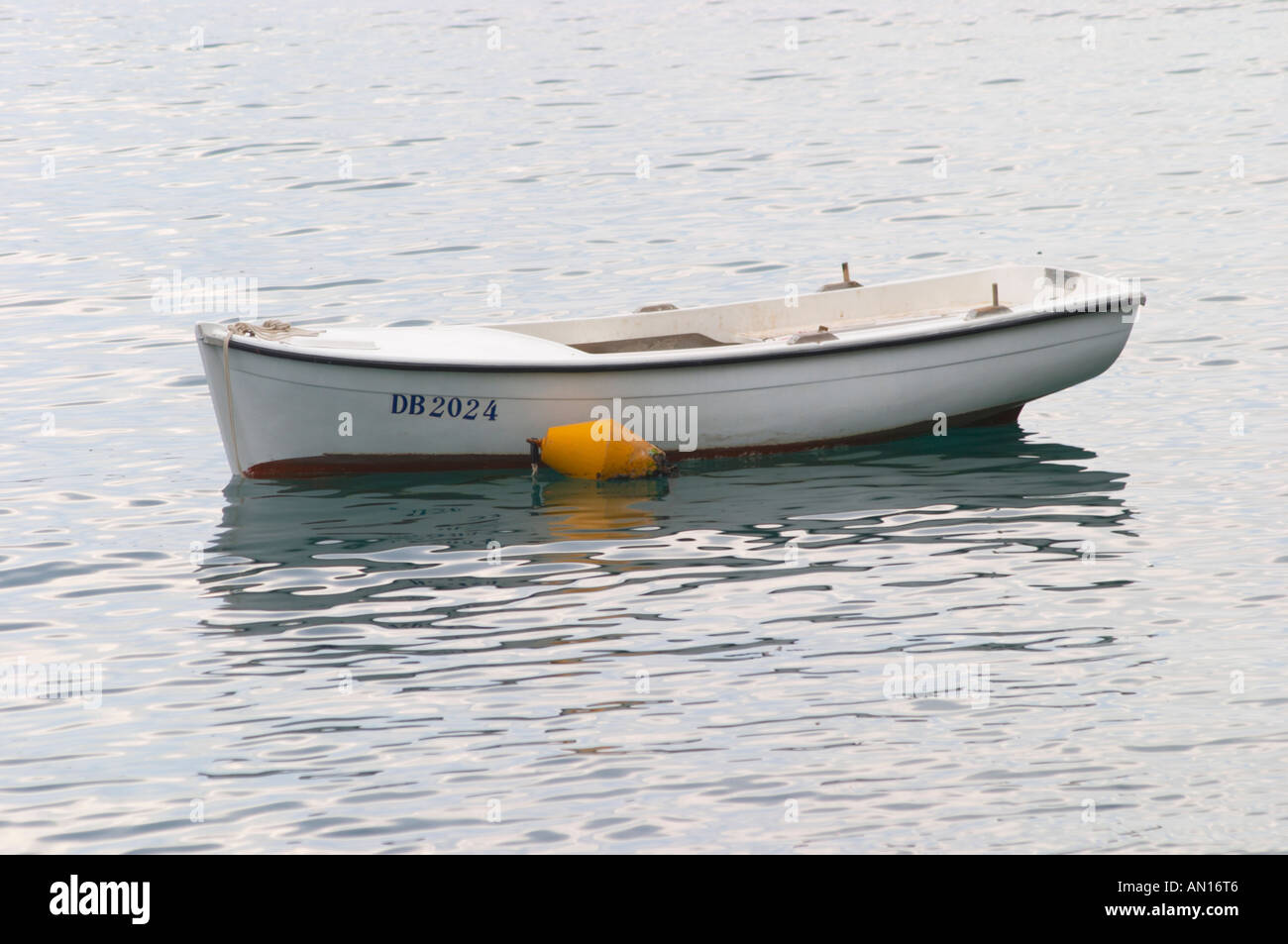 A white rowing boat moored by a yellow buoy Uvala Sumartin bay between ...