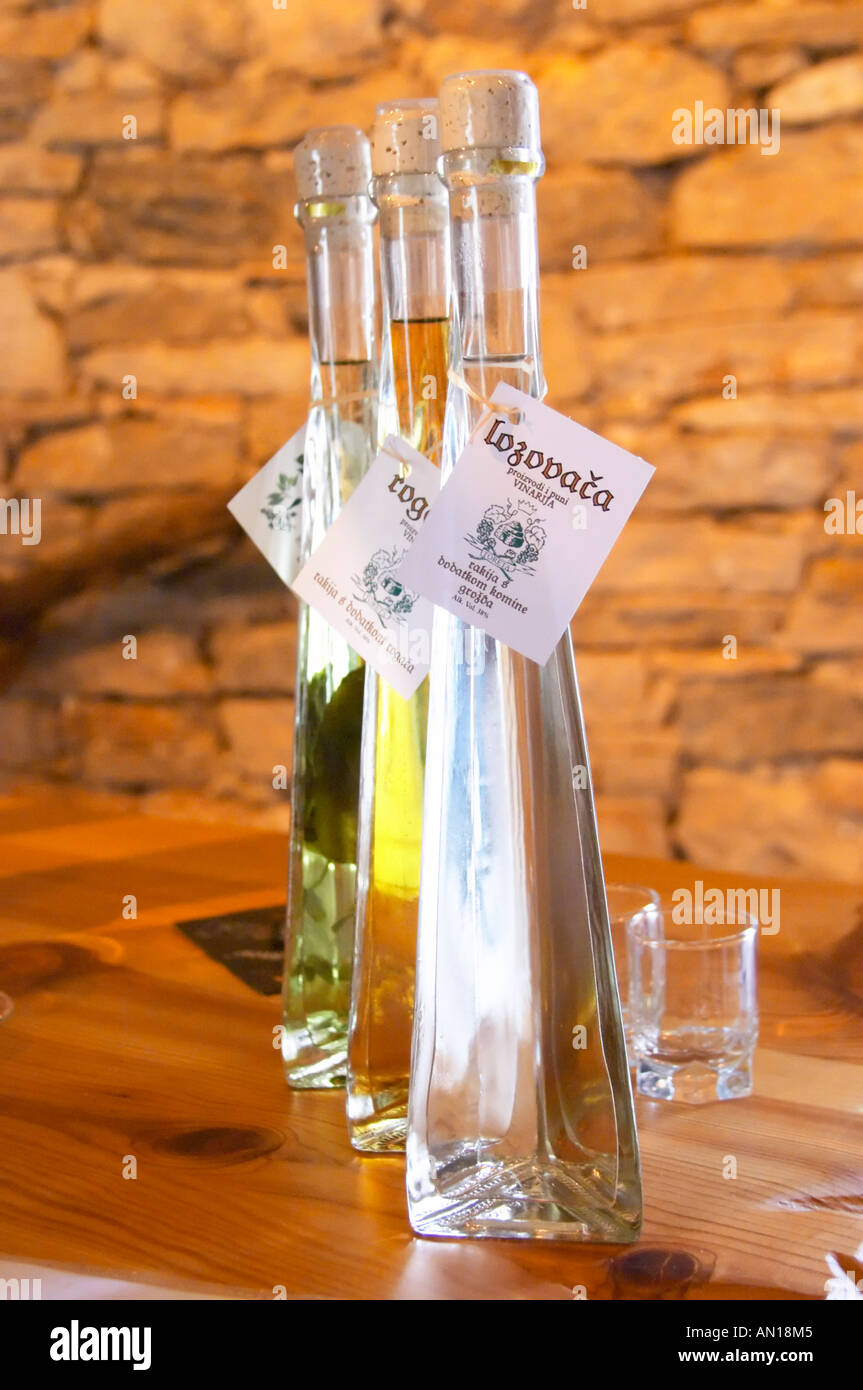 Bottles of rakija grappa type spirit clear and with herbs. Glasses on a ...