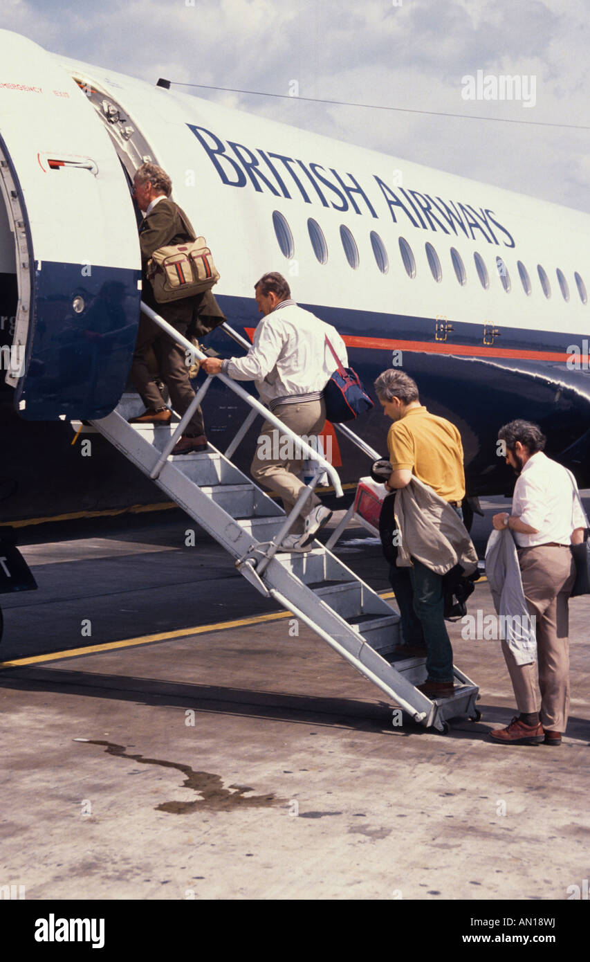 Passengers walking up steps to board aeroplane on airport runway Stock ...