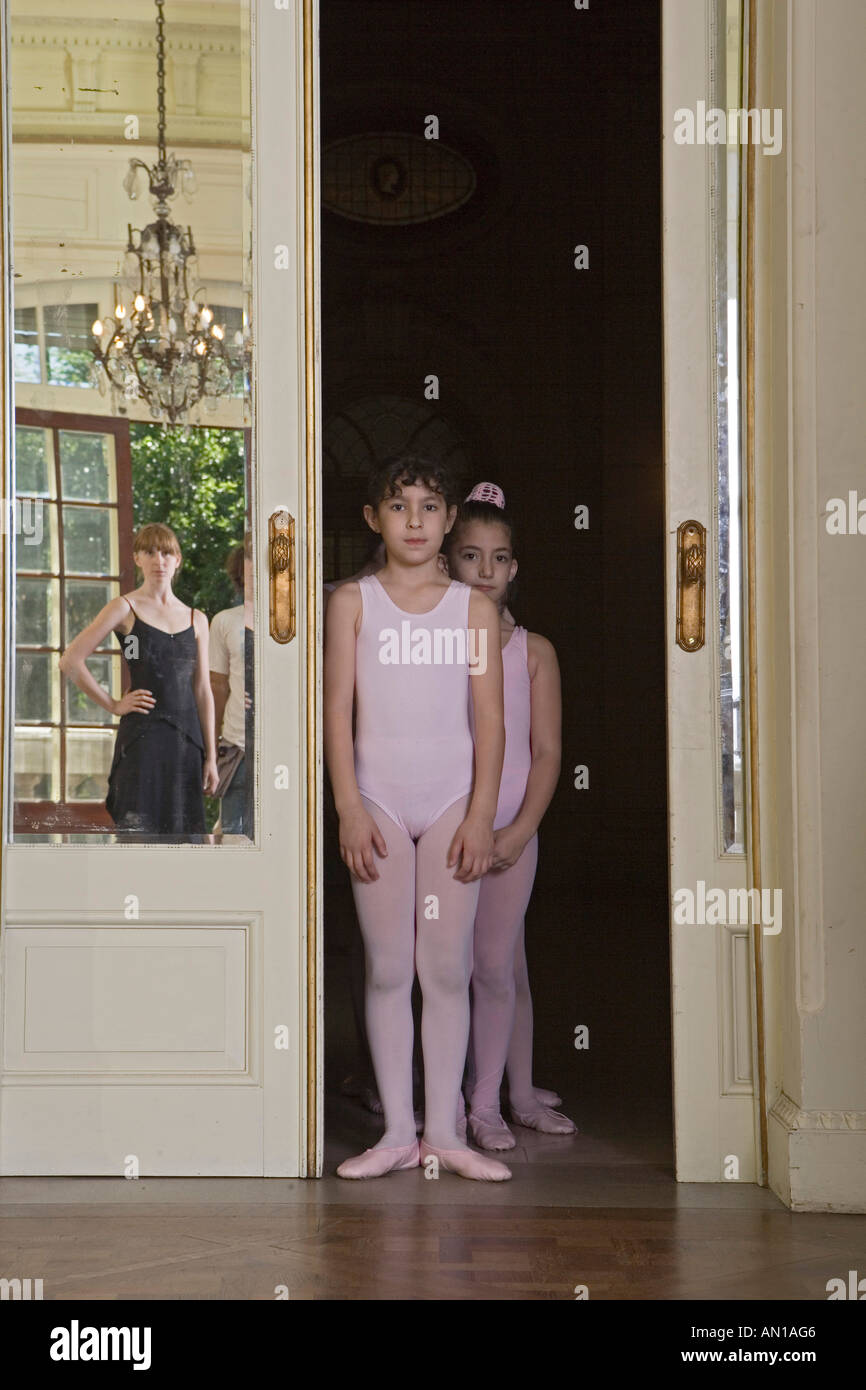 Young girls wait in doorway to enter ballet lesson as teacher looks on ...