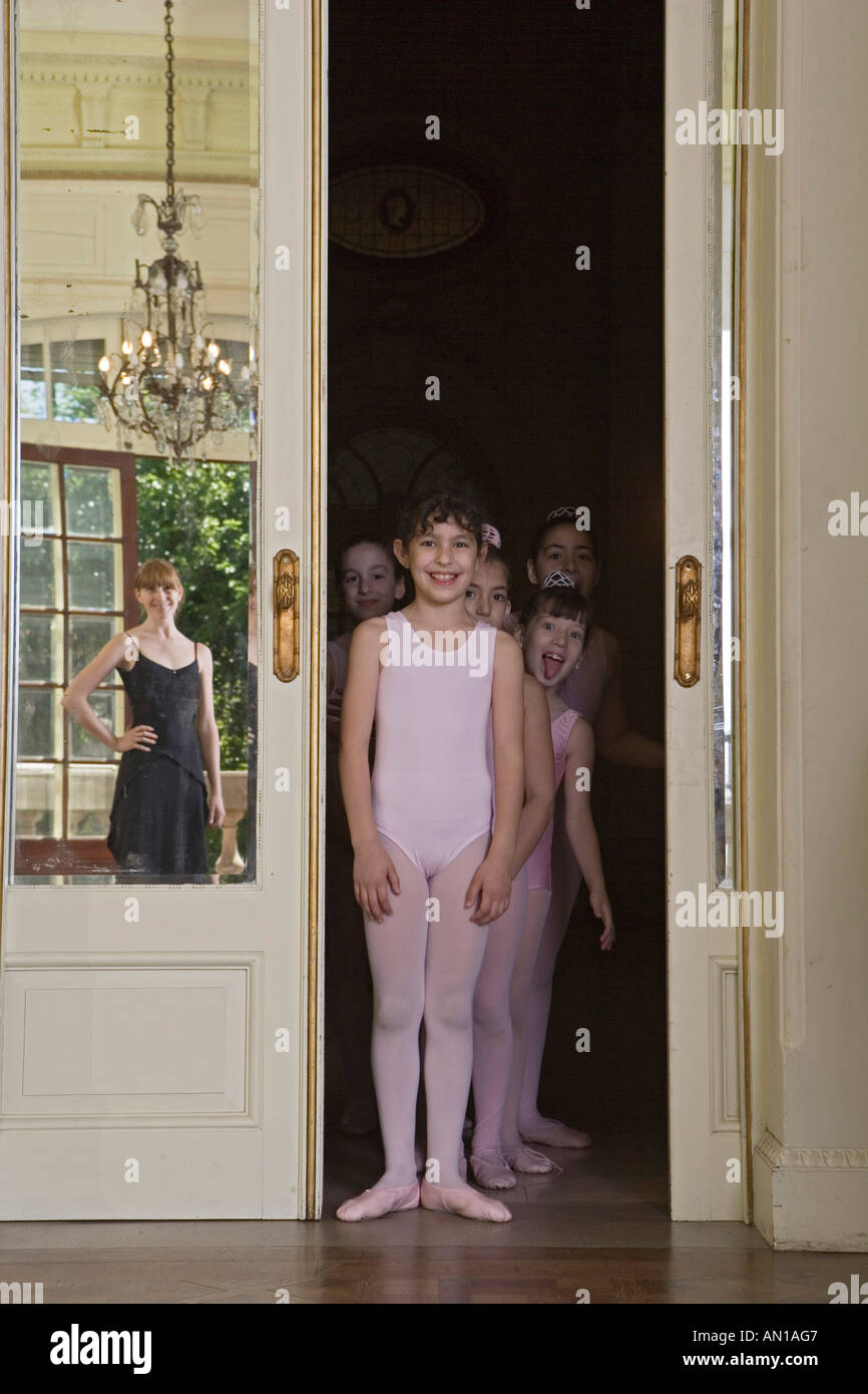 Group of young girls in ballet class making faces through doorway as ...