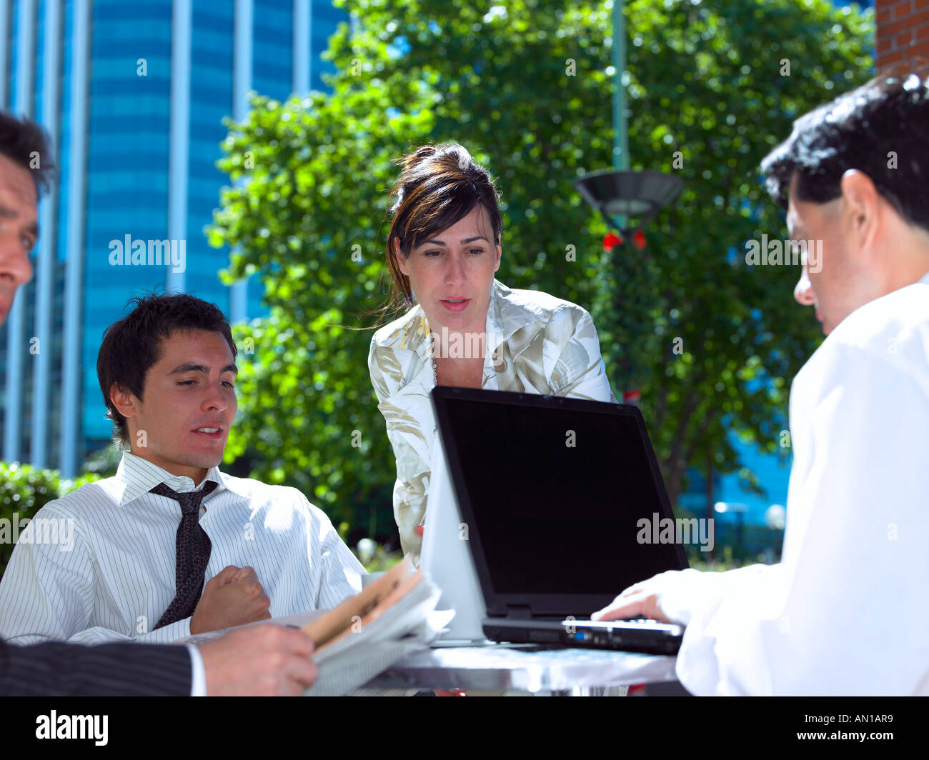 Four people sitting outside working Stock Photo - Alamy