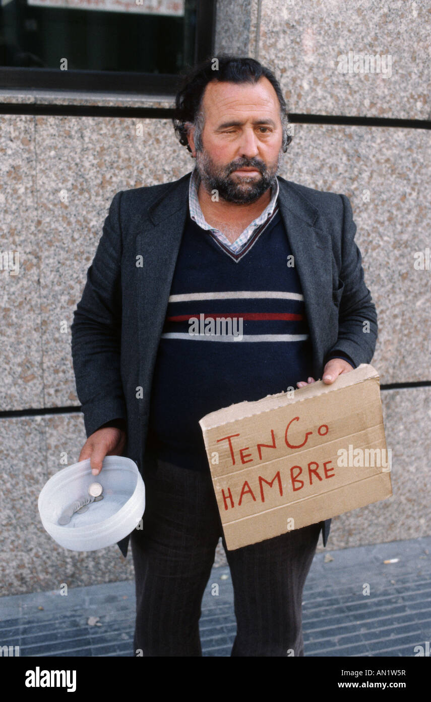Man begging in street in Barcelona, holding sign reading 'tengo hambre ...