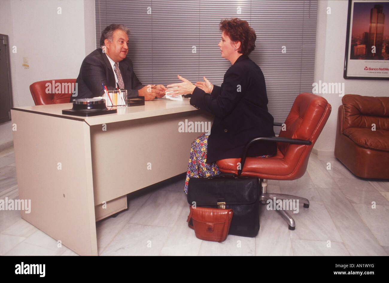 Business meeting between man and woman sitting across desk in office ...