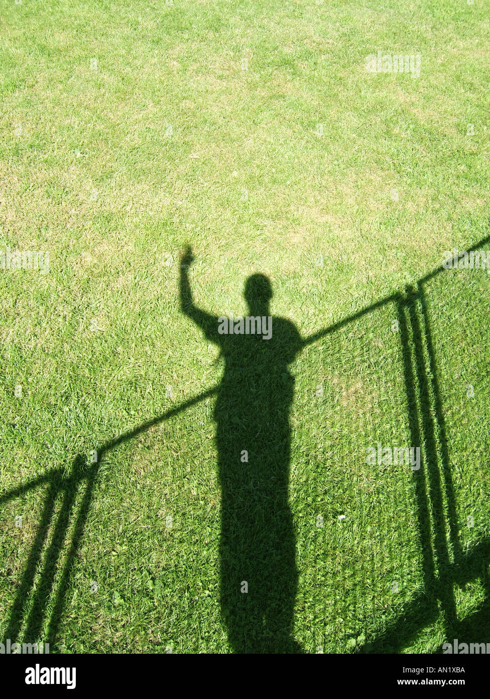 man waving shadow on grass with fence Stock Photo - Alamy