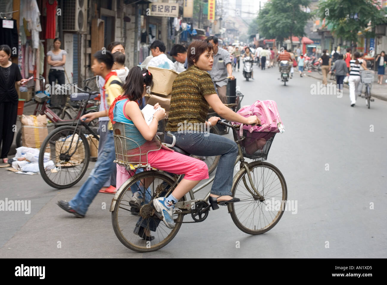 School child reading on the back of a bicycle in traditional chinese ...
