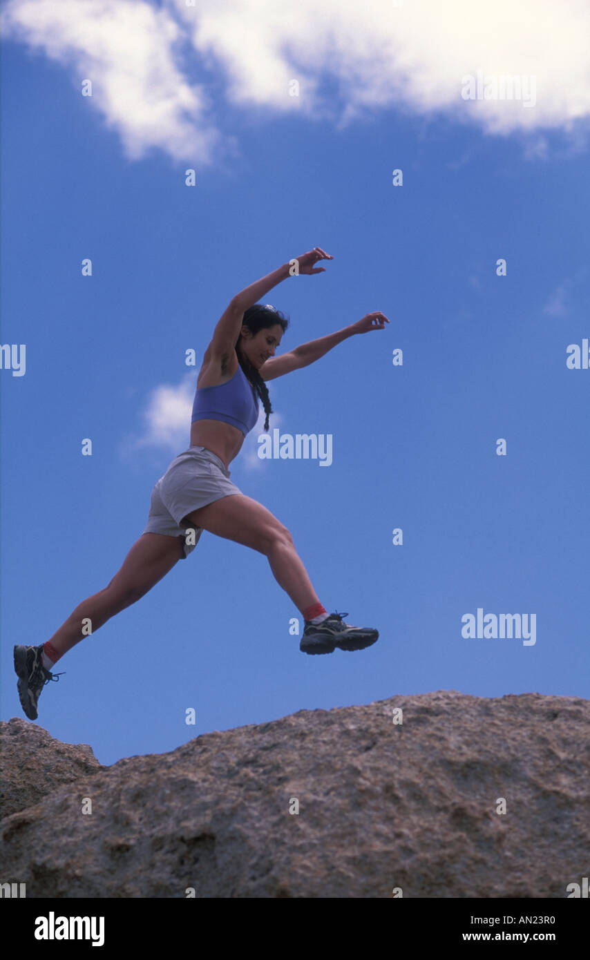 Woman hiker jumping over rocks Stock Photo - Alamy