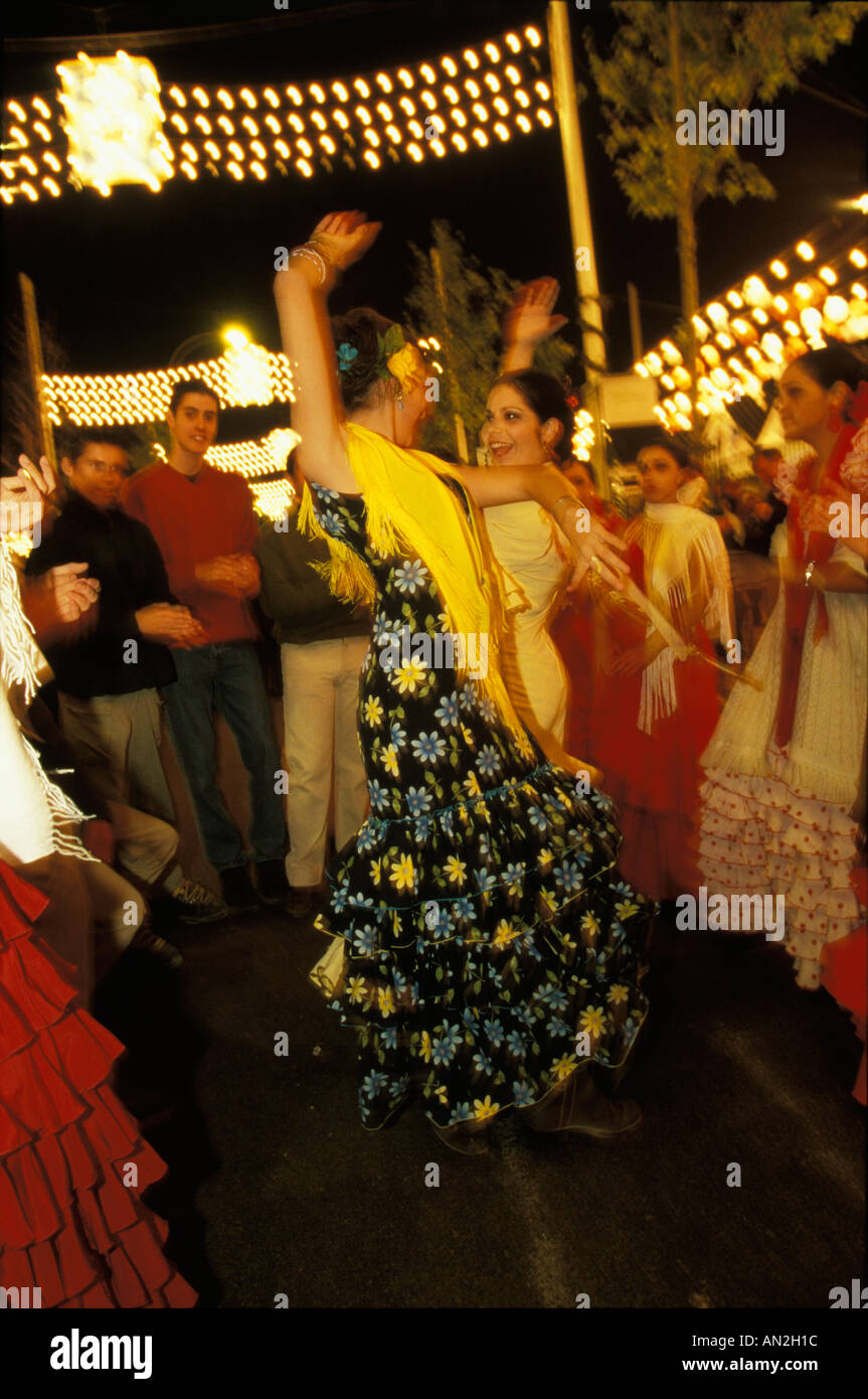 Young women dance the sevillana at night outdoors at the fairgrounds of ...