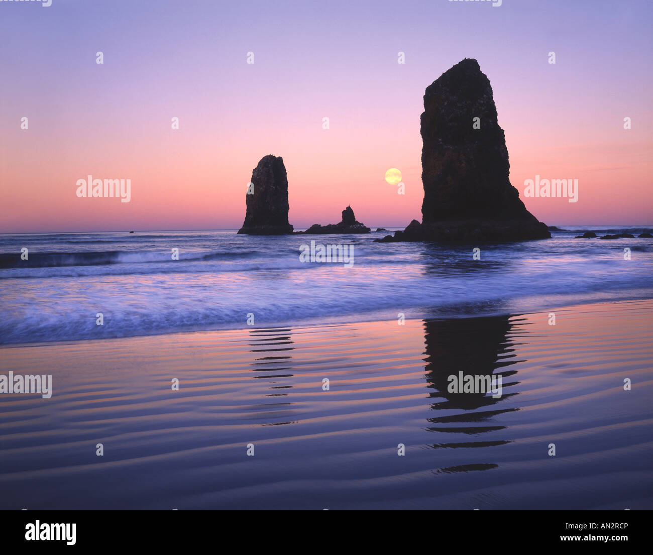 USA, Oregon, Cannon Beach, Moonset between The Needles rocks in early ...