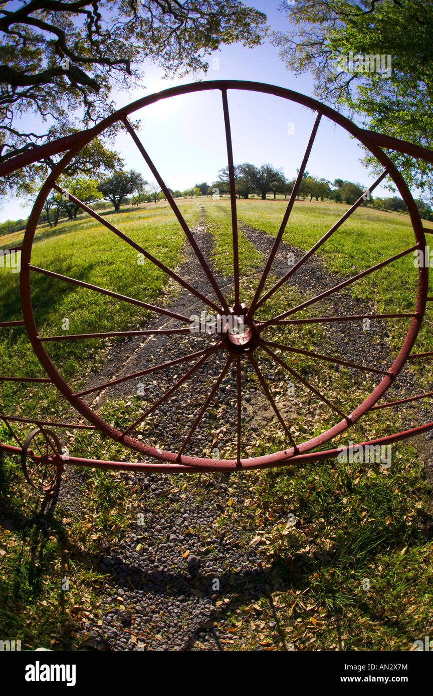 Gate with metal wheel looking through to two lane path in field near ...
