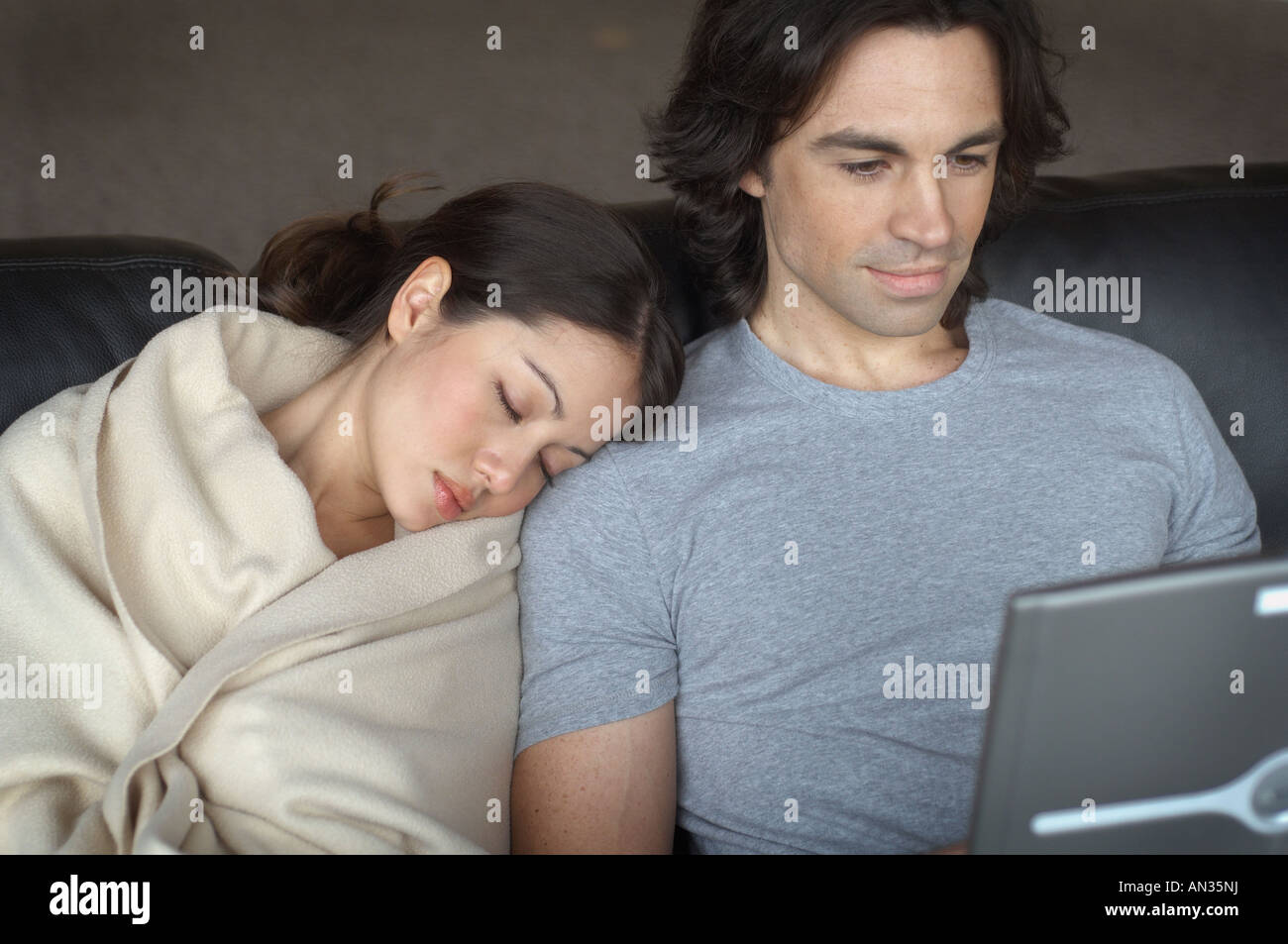 Multi-ethnic couple cuddling on sofa Stock Photo - Alamy