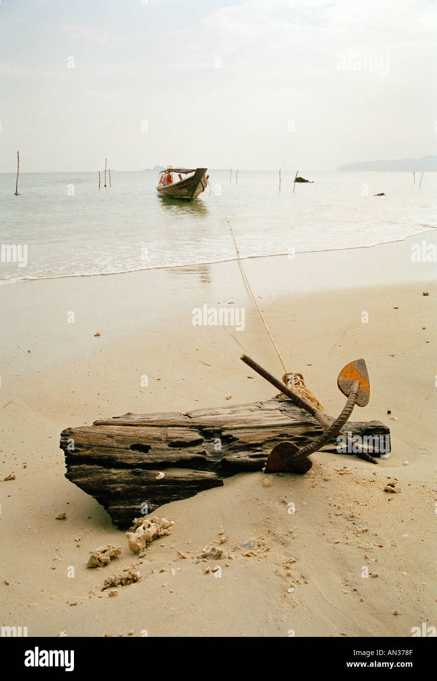 Anchor on beach with boat floating offshore attached Stock Photo - Alamy