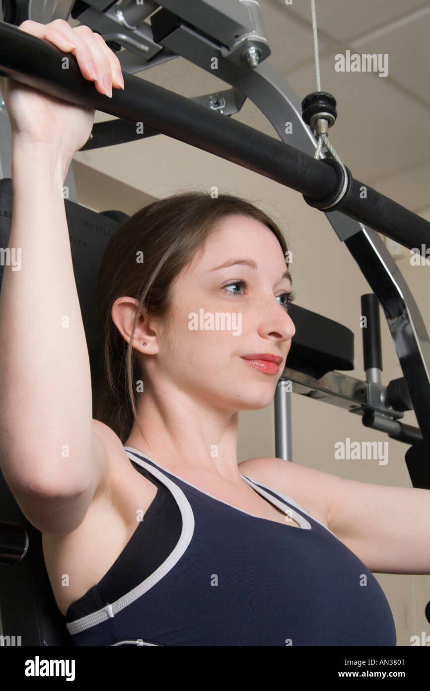 Young woman doing pull down exercise on weights gym machine Stock Photo ...