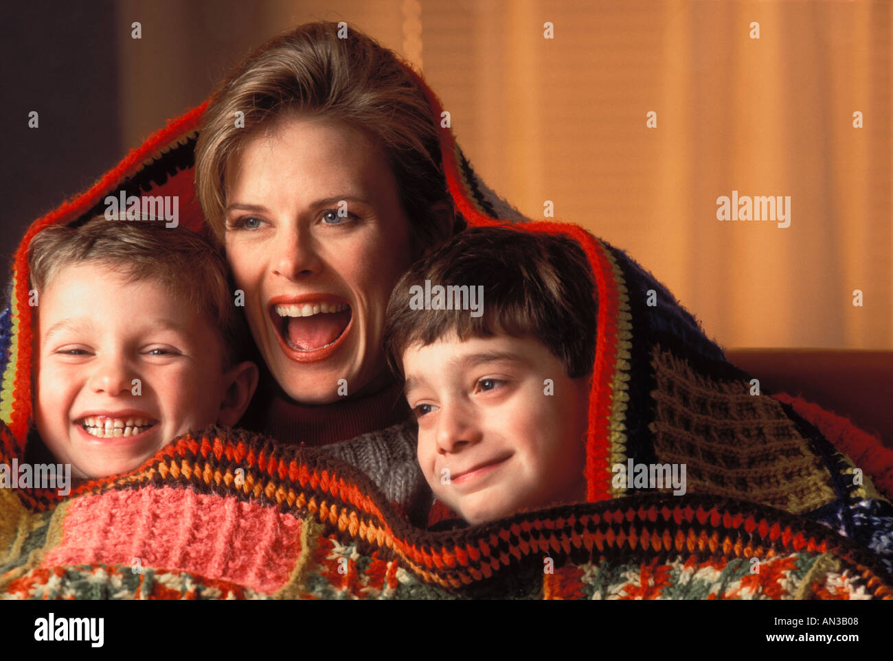 Portrait of mother and Her children Laughing and playing under blanket ...