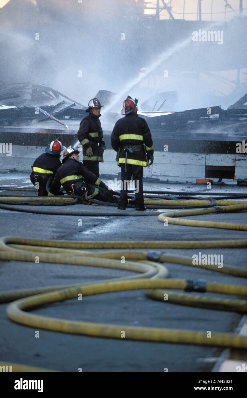 firemen hosing down rubble at fire scene Stock Photo - Alamy