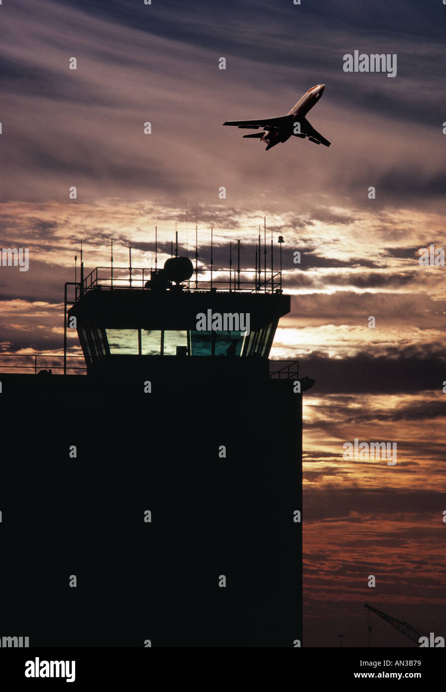 Plane taking off at sunset over control tower Stock Photo - Alamy