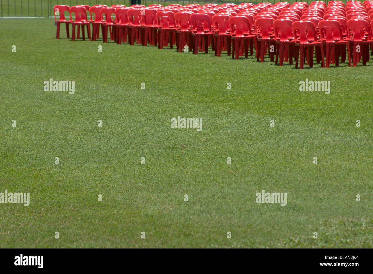 grass field with rows of red plastic chairs Stock Photo - Alamy