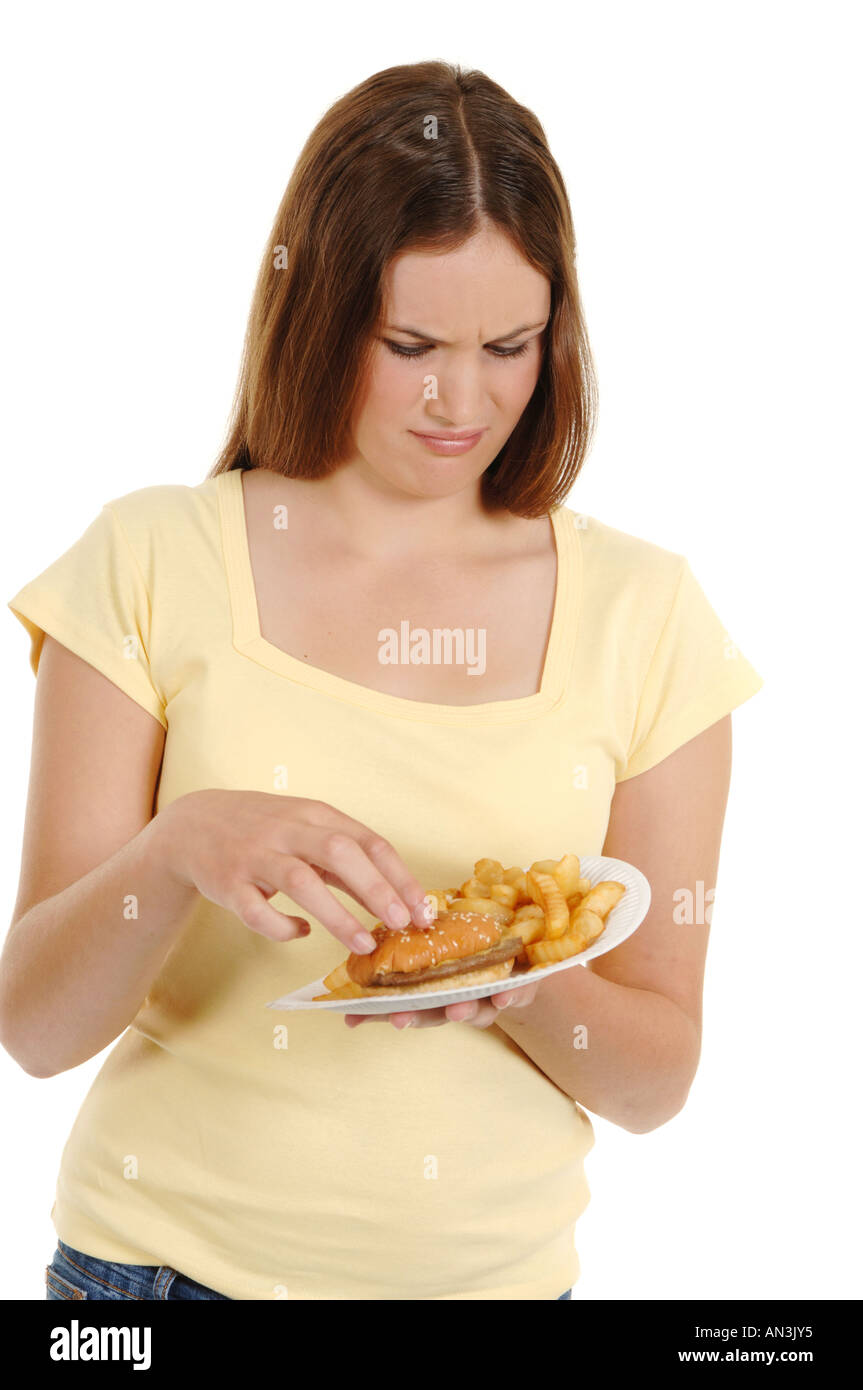 a teenage girl looking in a disgusted way at a hamburger and chips ...