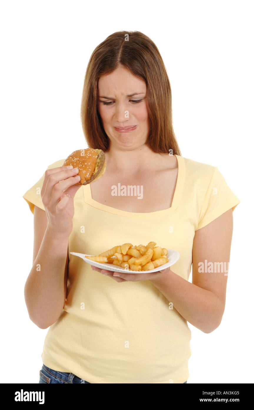 a teenage girl looking in a disgusted way at a hamburger and chips ...