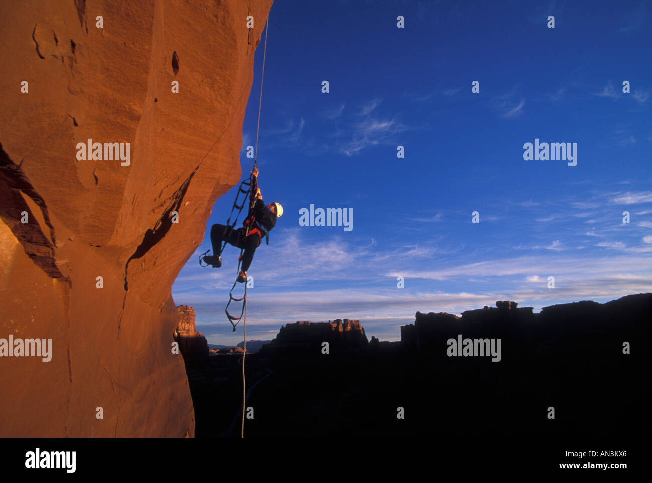 Rock climber ascending a rope next to a steep sandstone rock face Stock ...