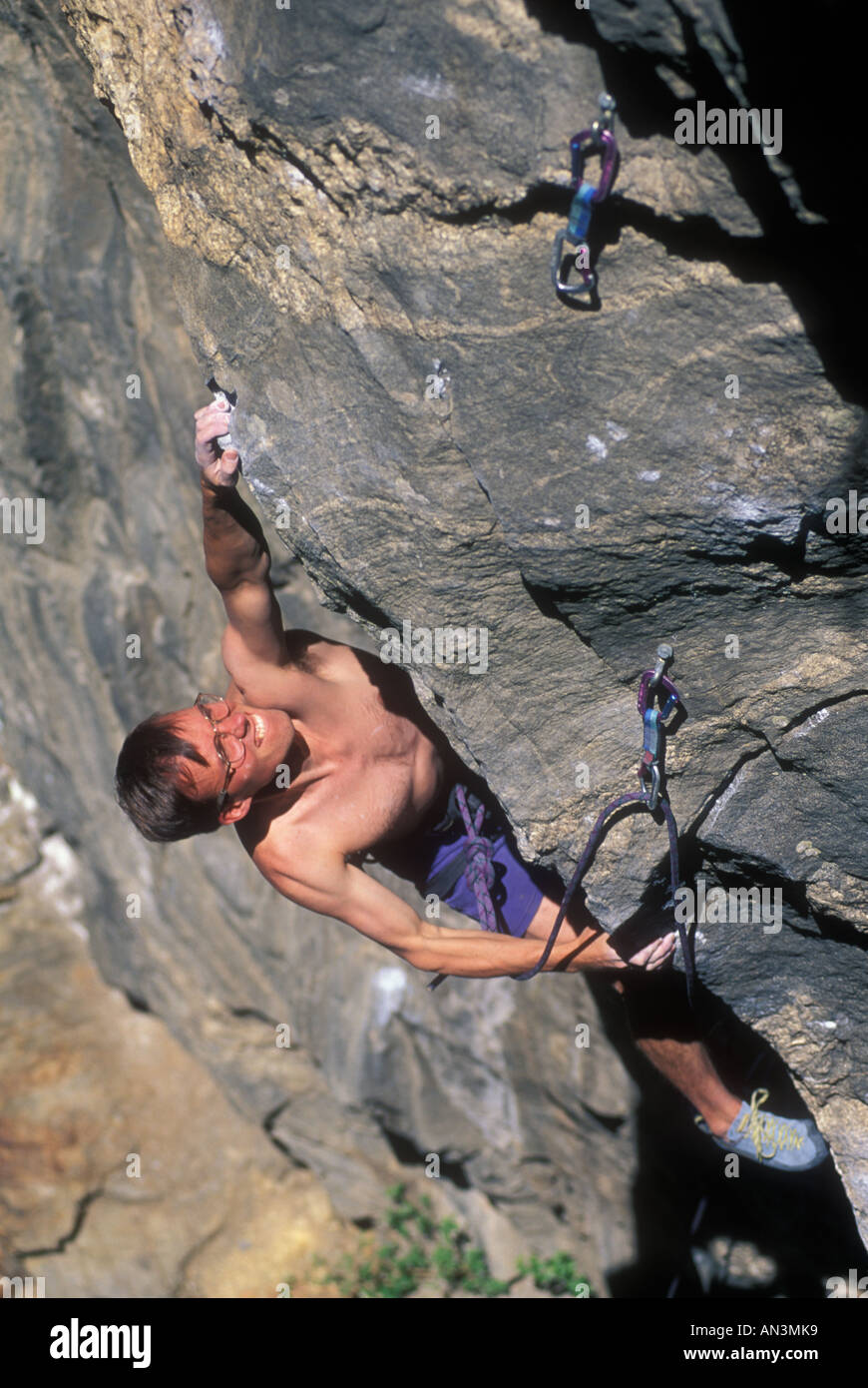 Rock climber climbing a steep overhanging rock face Stock Photo - Alamy