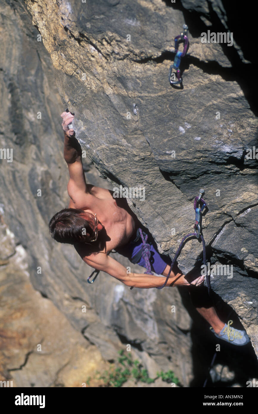 Rock climber climbing a steep overhanging rock face Stock Photo - Alamy