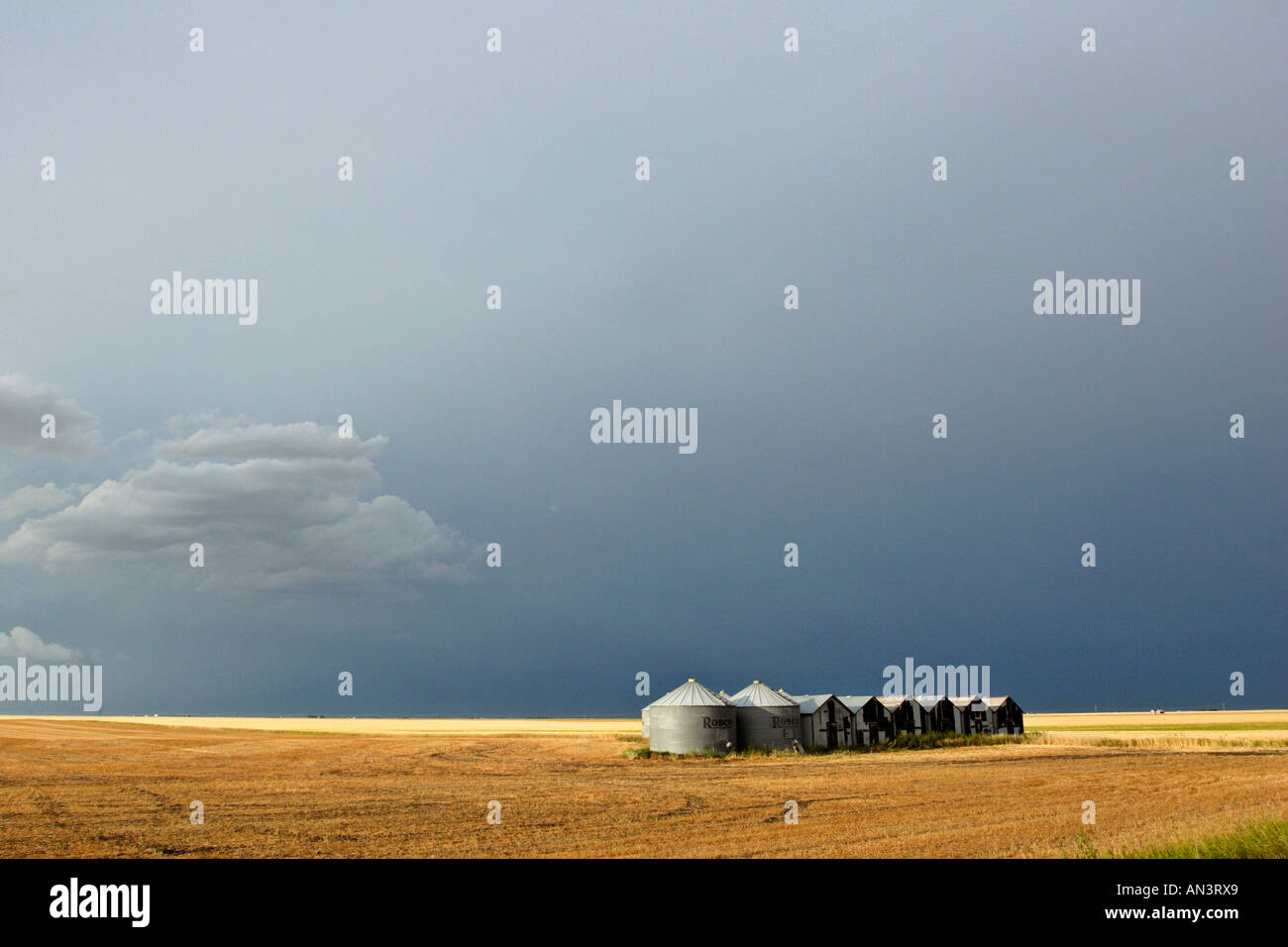 Grain storage bins and granaries with storm clouds approaching in ...
