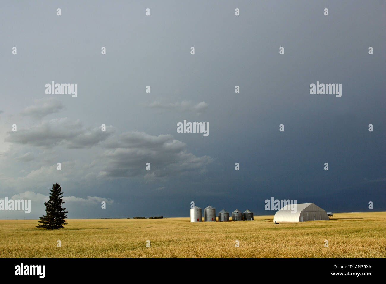 Grain storage bins and a garage with storm clouds approaching in scenic ...