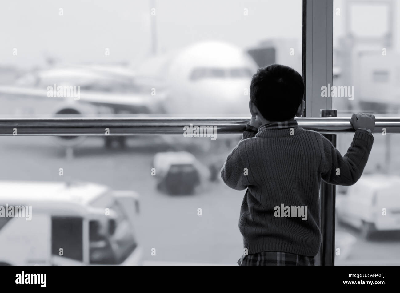 Child alone at the airport looking at a plane through a window Stock ...