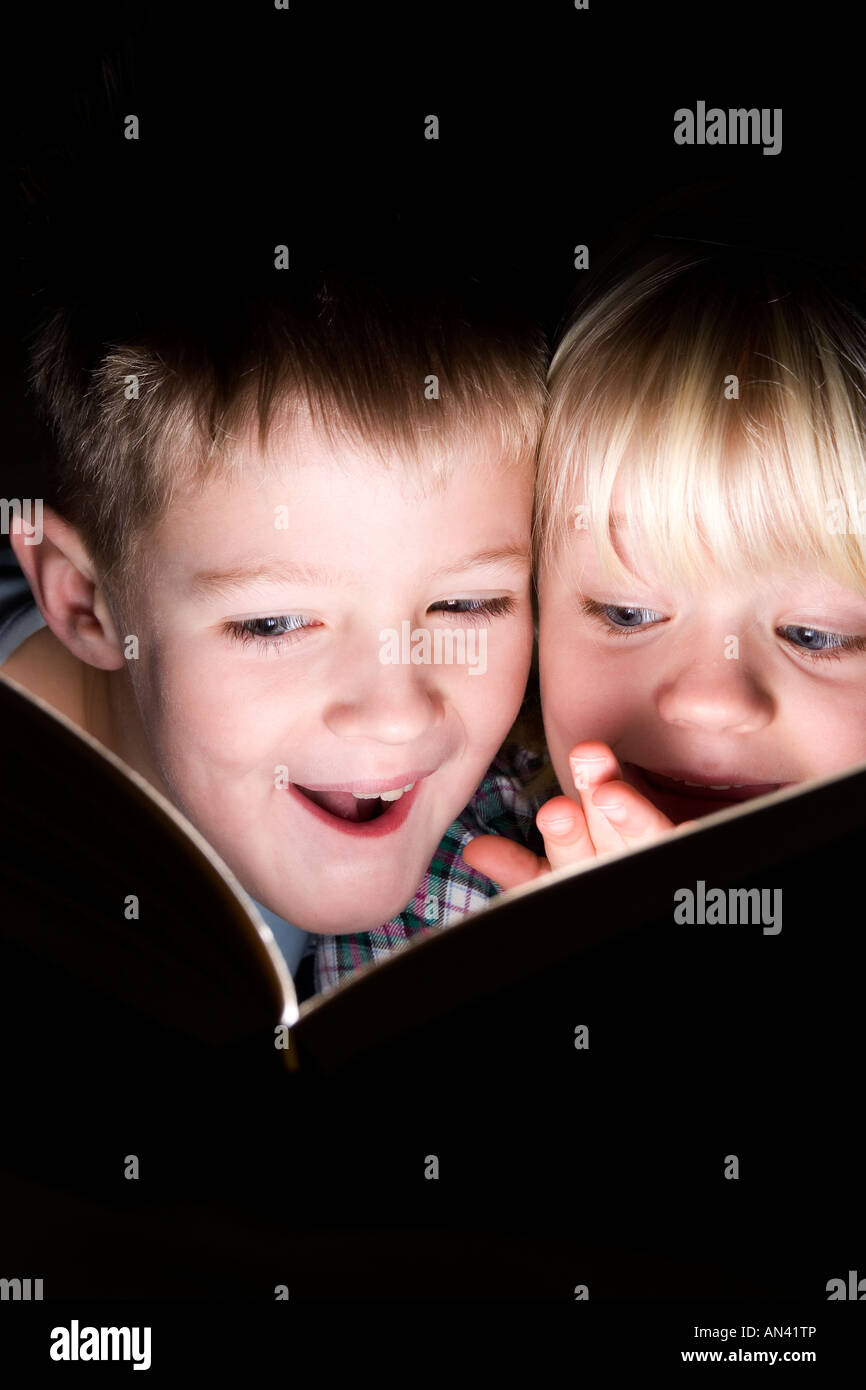 boy and girl reading book by torchlight Stock Photo - Alamy
