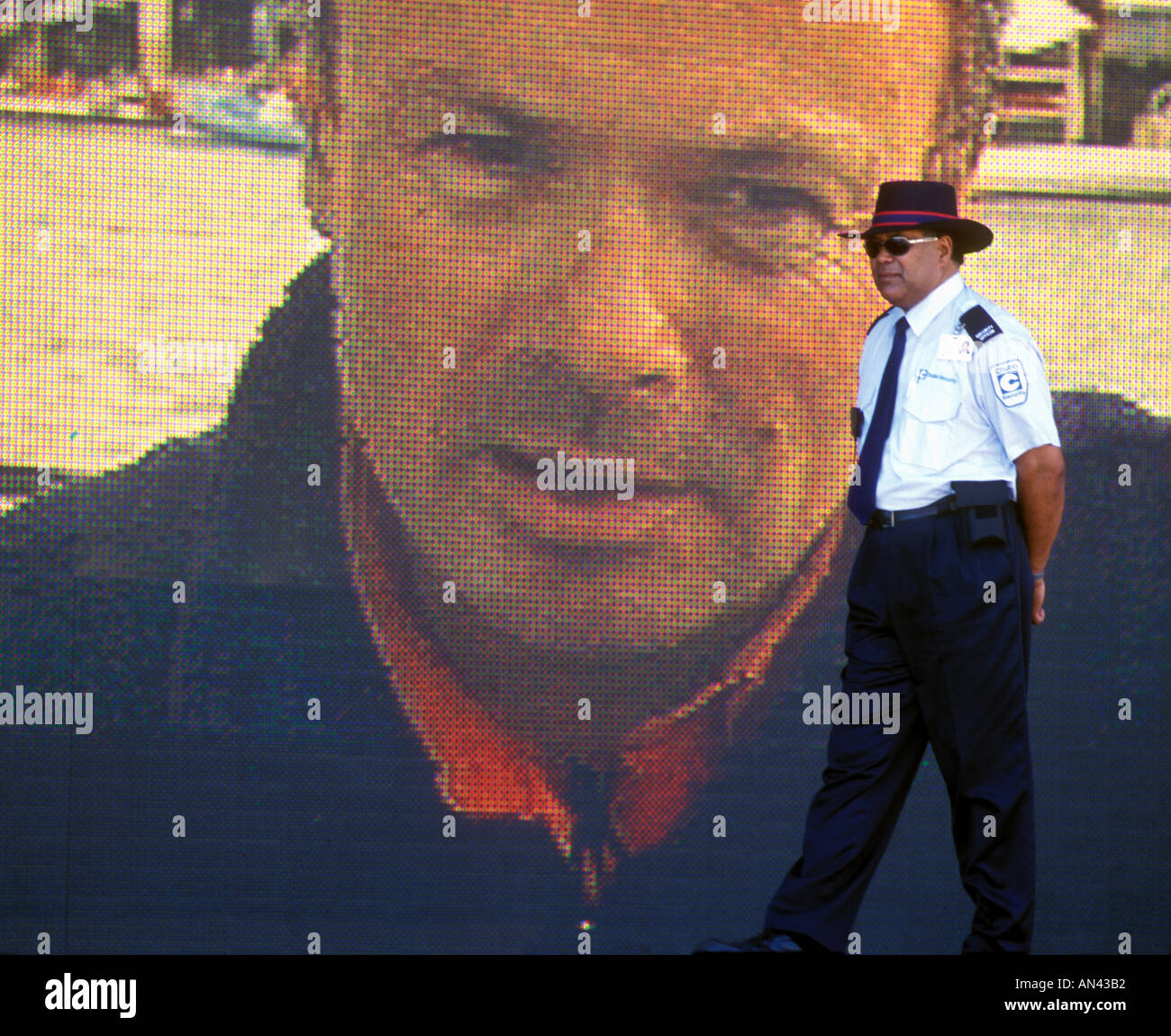 A security guard walks in front of a large TV screen in the America s ...