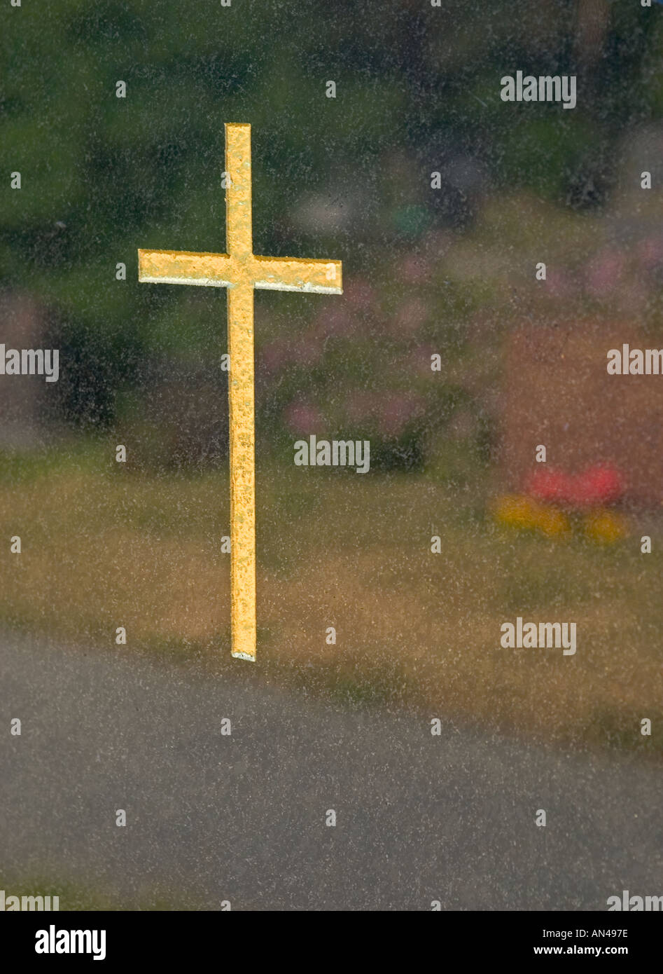 Golden cross on tombstone and reflections of the flowers on the grave ...