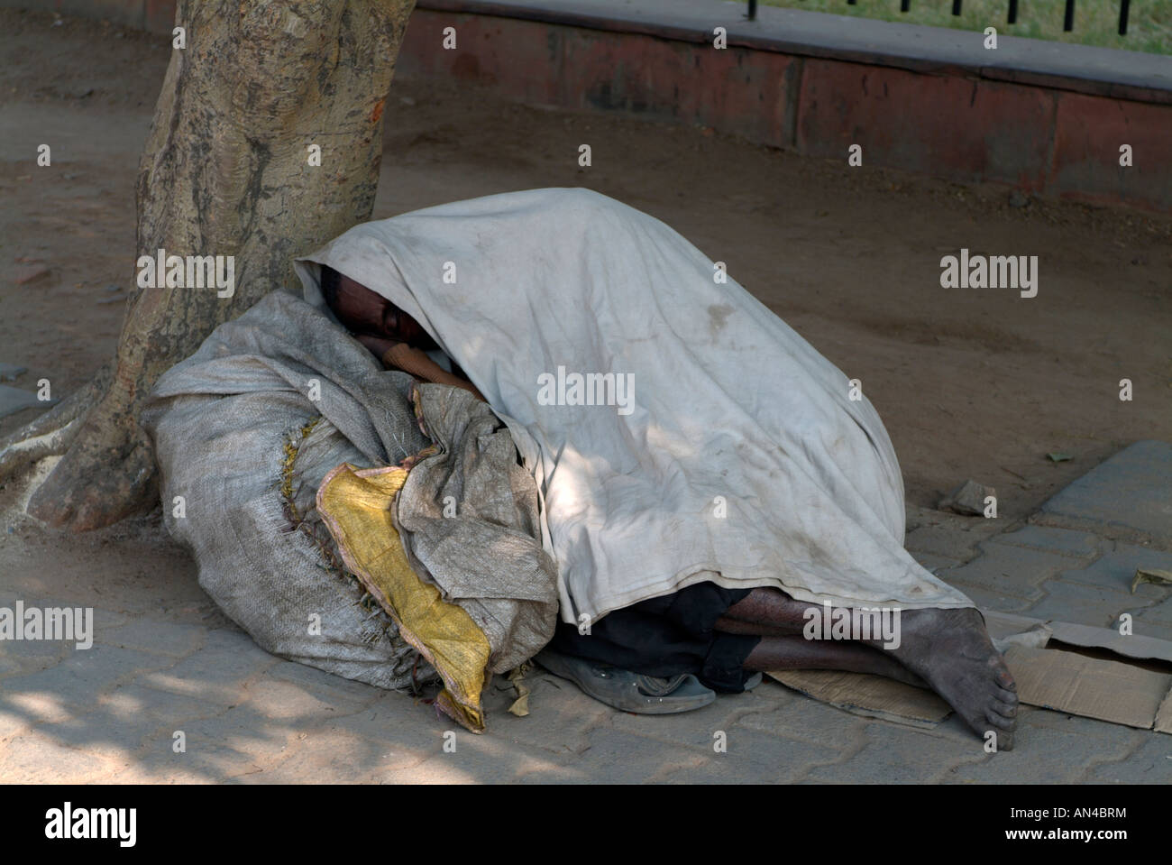Destitute homeless poverty stricken man sleeping under a sack beneath a ...