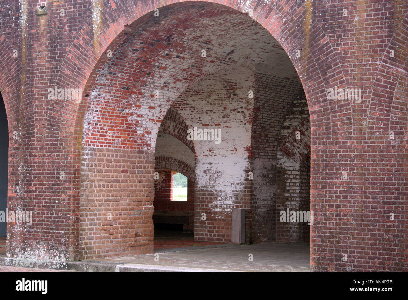 Arched passageway of red brick with white paint, collums and windows ...