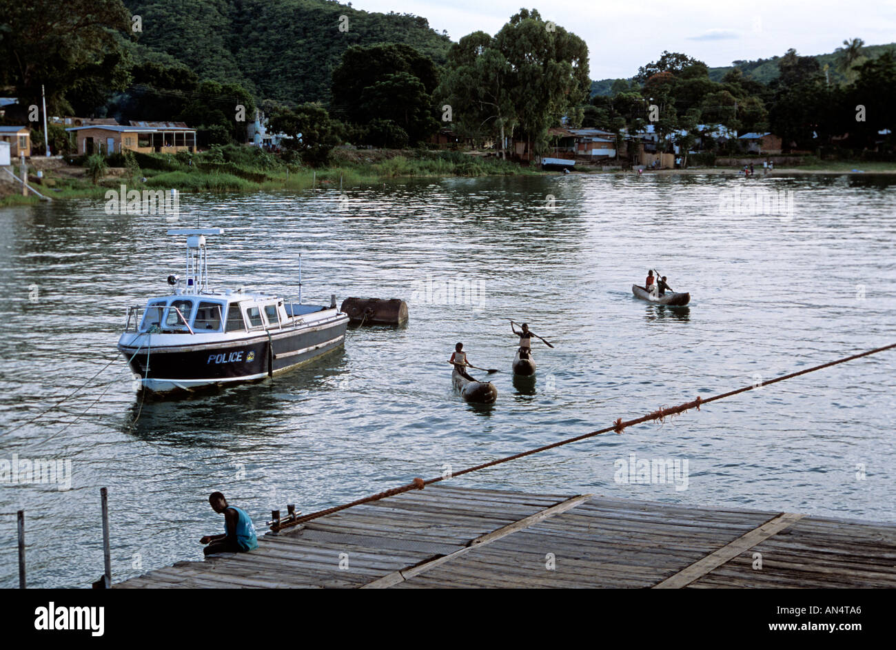 A police boat floating along with villagers canoes Stock Photo - Alamy