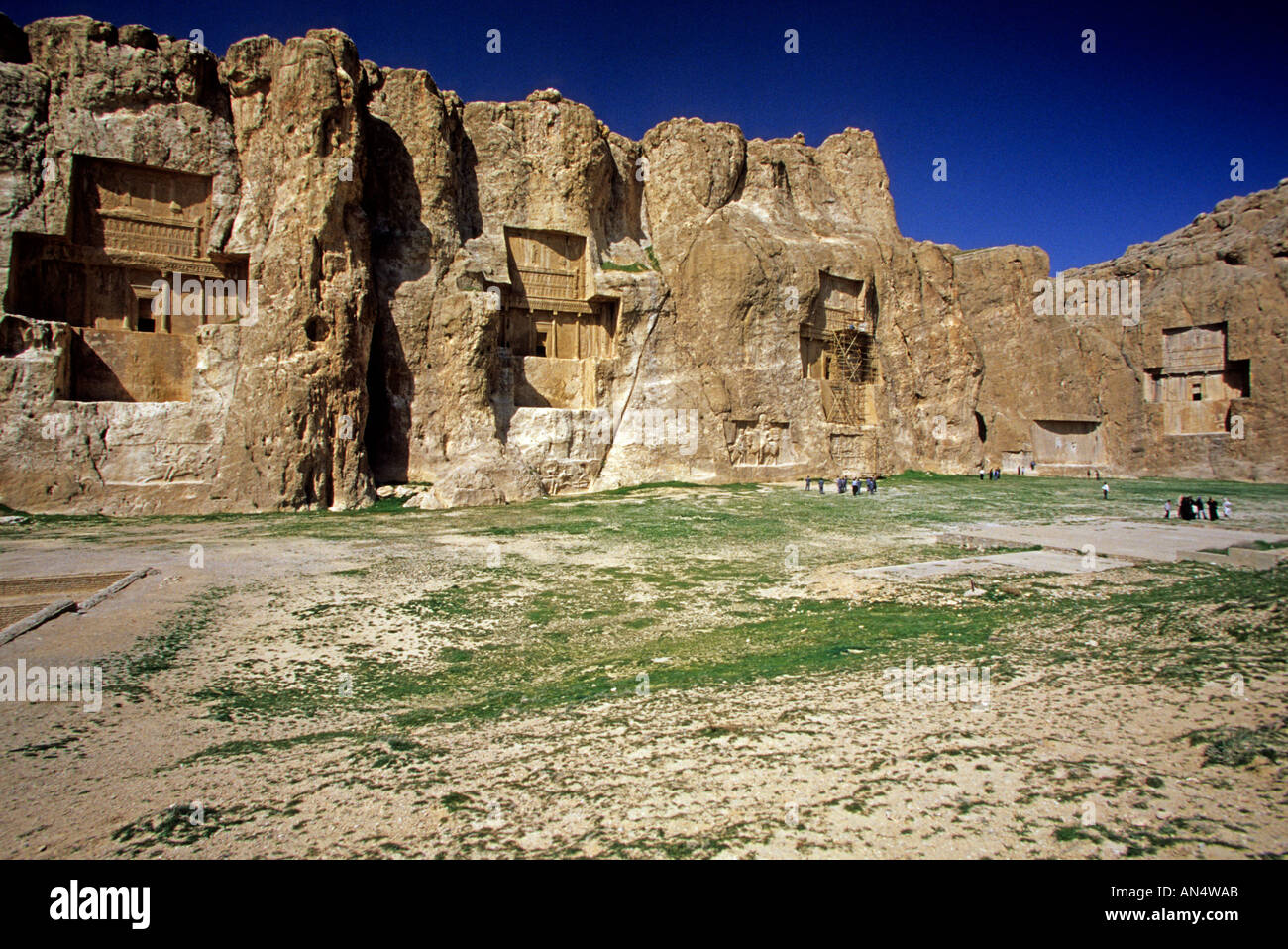 Tourists at cross shaped ancient Iranian rock reliefs cut into the ...