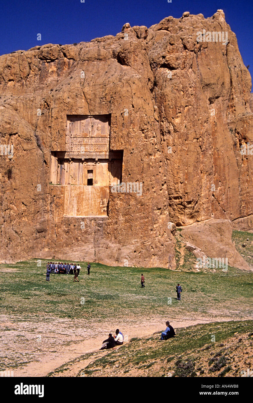 Tourists at cross shaped ancient Iranian rock reliefs cut into the ...