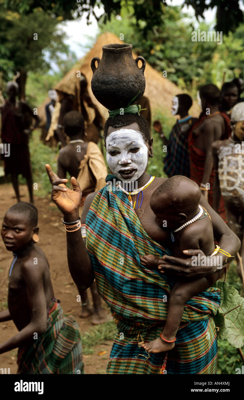 A young surma woman breastfeeds her baby as she walks towards the river ...